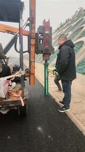 Science, Technology & Engineering on Instagram: "Workers are shown installing metal highway guardrail posts using specialized machinery, driving a green post into the ground along a newly paved road with a reinforced slope. These guardrails, made from galvanized steel, are critical road safety infrastructure designed to prevent vehicles from skidding off the road and to absorb impact forces. The video also captures a moment of industrial fabrication, where a forklift is used to bend a thick meta