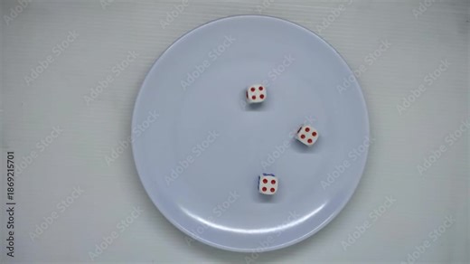 Triple four-value dice. A person reaches into the frame to pick up the dice from the plate, shakes them in their hand, and rolls them onto the white plate until they get three fours.