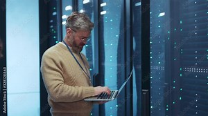 Handsome experienced technician opening rack of server cabinet downloading server update network operation collaborating with colleague at data center.