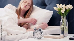 Selective focus of sleeping woman turning off alarm clock