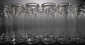 Large number of empty glass vials for vaccines stands in rows on table surface. Professional glassware for medical purposes and laboratory investigations