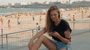 Happy girl audio message ai helper student using a smart phone in a city park sitting on a bench beach coastline, young woman smiling use application. voice message, recognition speech