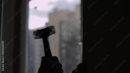 Worker tapping window frame with rubber mallet during installation