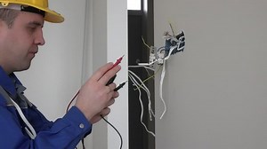 Electrician checking socket voltage using multimeter in a wall fixture socket. Static shot. 4K UHD