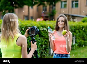 Two teenage girls. Summer in nature. In her hands holds bottle of water and an apple. The concept of healthy eating. Young bloggers record video for t Stock Photo - Alamy