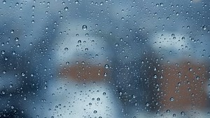 A rainy view through a window, blurred background with water droplets, creating calm atmosphere