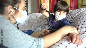 4K Lockdown health care - Child and mother in masks learning how to use manual sphygmomanometer