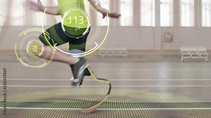Tracking shot of paralympic athlete with prosthetic leg running on track; digitally animated pulse and speed projections appearing on his knee and hip