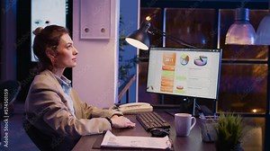 Business manager looking at metaverse hologram, using holographic 3d environment to plan financial development at night. Young employee checking economy diagrams statistics. Handheld shot.