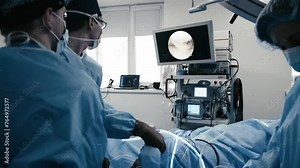 Professional surgeons perform the operation in a modern surgical operating room and monitor the process in front of monitors. Modern medical technologies, operation and surgery department.