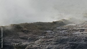 Erupting geyser with hot thick steam. Natural physic science 4K. Slow motion of cinematic boiling water splashes spilling in different directions form the muddy sulfur geyser in Yellowstone volcano