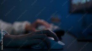 Detail cropped shot of female gamer playing video game at computer in dark virtual room at night. Close-up of unrecognizable business woman clicking on modern wireless computer mouse, slow motion.