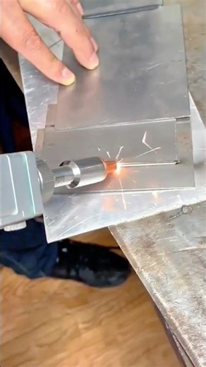 welding and joining two thin silver metal plates together using a handheld laser machine