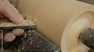 professional carpenter is using skew chisel for shaping piece of wood. wood tuning lathe at work. shaping piece of wood on wood turning lathe at workshop. close up view