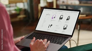 Over Shoulder Person Using Laptop Computer, Online Shopping for Electronics, Wireless Hi-Fi Headphones. e-Commerce Concept of Purchasing, Buying, Ordering Tech Devices on Website. Close-up Shot