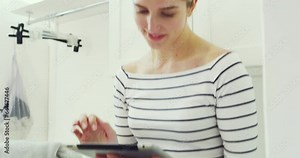 Woman, tablet and sitting on laundry machine for break or relax on social media or internet scroll at home. Person, washing or touchscreen for technology, peace and happiness with housekeeping on web