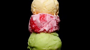 Time lapse, Melting of three flavors of ice cream on a cone. Ice cream water flows from the cone. On the black  background.