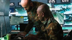 Military dispatcher helped by coworker with tablet to gain info from army intelligence analysts. Army intelligence corps expert discussing with colleague in command post, camera A
