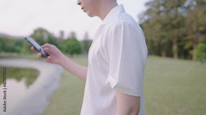 Closeup a male hands touching on phone screen while relaxing walking in natural park, head down using portable information technology device, recreational activity outdoor, people go online concept