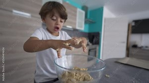 Cute child with messy hands while preparing dough. Kid cooking food dirty hand