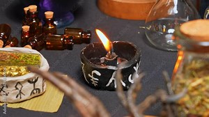 Witchcraft still life focus shift with black burning candle in the cup with magic symbols. Esoteric gothic and occult witch craft for Halloween. Various magic objects and ritual arrangement. Stock Video