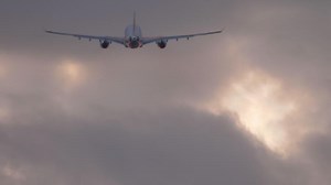 Cinematic footage of an airliner gaining altitude in a cloudy sunset sky, rear view, long shot. Jet in the sky. Airplane taking off.