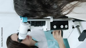 Attentive optometrist examining beautiful female patient with slit lamp in ophthalmology clinic. Optometrist during an examination in a modern clinic. Eyesight check