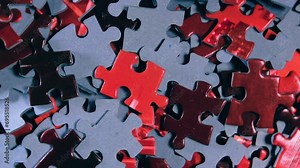 Background of Colored Puzzle Pieces that Slowly Rotating Counterclockwise - Top View, Close-Up. Texture of Incomplete Red and Grey Jigsaw Puzzle - Left Rotation