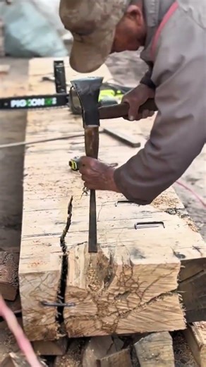 A person is splitting wood logs using wedges