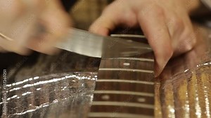 Guitar maker grinds musical frets on the fingerboard of the guitar