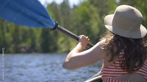 Beautiful young woman kayaking on lake. Girl rowing oars on a kayak on the river. Sports hike, water rafting in nature.