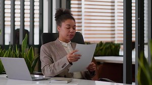 African American woman ethnic businesswoman boss business employer manager in office workplace bank company dissatisfied serious girl female read document report crumple paper throwing away failure