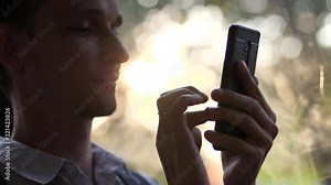 Man goes by tram transport sit by window slide smartphone social media page on sunset light haze