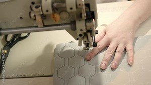 process of embroidering diamond pattern on cowhide in atelier for helicopter or car seats on step sewing machine. Creating unique interior design from personal brand. designer sits and sews on fabric.