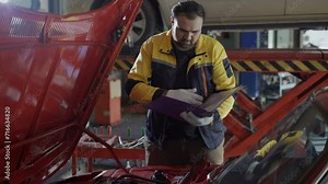 Mechanic in causing electronic equipment.r repair shop repairs car using laptop, repairs damaged car Check for defective components