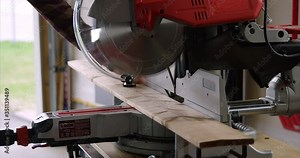 Handy man uses mitre saw to make a chop cut on a piece of wood - slow motion