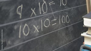 Mathematics lesson on blackboard with chalk and books on background panning shot