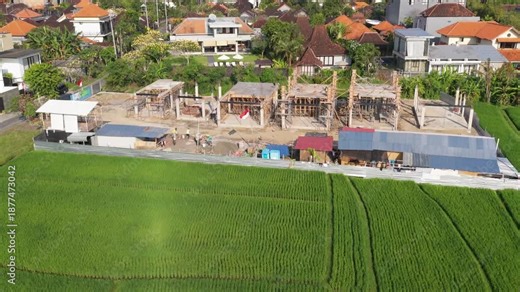 Drone footage showing active building construction bordered by lush farmland and dense suburban housing