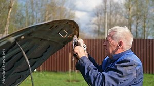 Car body shop. Repair man processes the welding seam using an angle grinder on replaced car part. Professional Body master grind old paint and rust. Rust damage. Rusting car. Hands with tool close-up