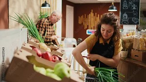 Diligent eco friendly grocery store employee restocking shelves with fresh fruits and vegetables. Local neighborhood supermarket storekeeper adding organic farm grown food on display
