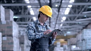 Worker male warehouse worker engineer man in a helmet working on the construction site of the warehouse, tablet computer, checking the warehouse, inspection of goods