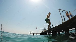 An inspiring down up view of a young man doing a back summersault on a Turkish resort in summer in slow motion.