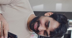 Vertical shoot. Adult man sitting at background and using phone for online mitting. Young buisinessman cooperate with colleaques via video call. Consept of online learning and work.