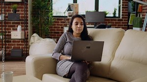 Teleworker lying on couch, remotely performing tasks in personal office. Relaxed freelancer inputting data on laptop while working from home, camera A dolly in close up shot
