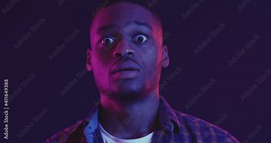 Shock expression. Close up of scared african american guy pulling back with big eyes, neon light background