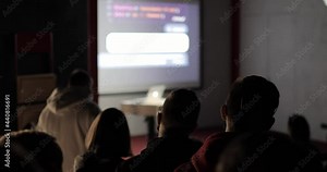A group of young people listening to a lecture seminar of a teacher-trainer using a projection screen and laptop. Education concept.