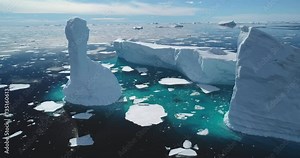 Melting iceberg towering in blue water bay, Antarctica sunny day landscape. Broken ice from glacier floating in polar ocean. Ecology, melting ice, climate change and global warming. Aerial drone shot