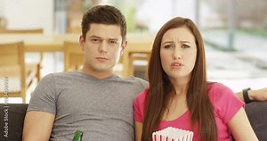 4K Young couple watching TV at home, insensitive boyfriend rolls his eyes when girlfriend gets upset. Slow motion