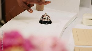Hotel guests ringing service bell at front desk reception, calling for receptionist of tropical resort staff to help with booking reservation. Couple arriving in lobby. Close up. Handheld shot.