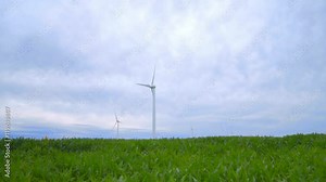 Wind farm in green field. WInd turbines farm. Wind technology. Green energy concept. Wind generators on farm field generating electricity. Wind power station. Wind power plant. WInd power generation